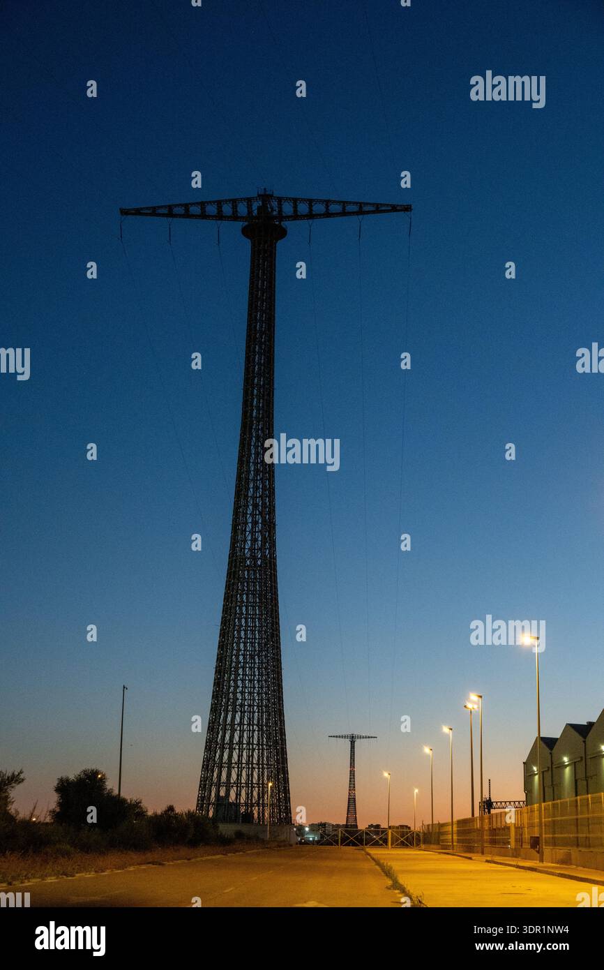 Tall lattice electricity transmission pylon silhouetted at dusk near ...