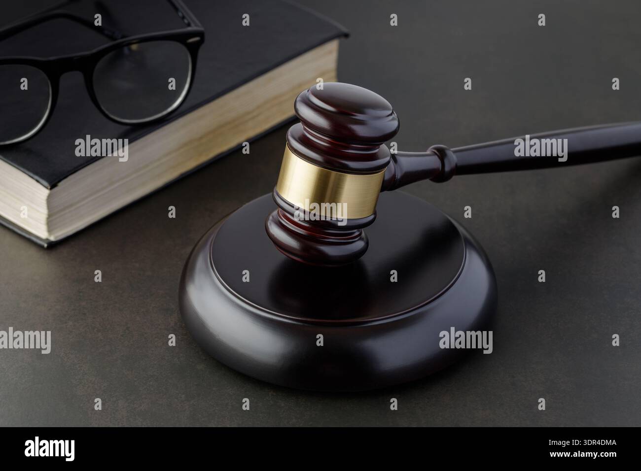Brown golden wooden gavel of judge on dark table with black book and ...