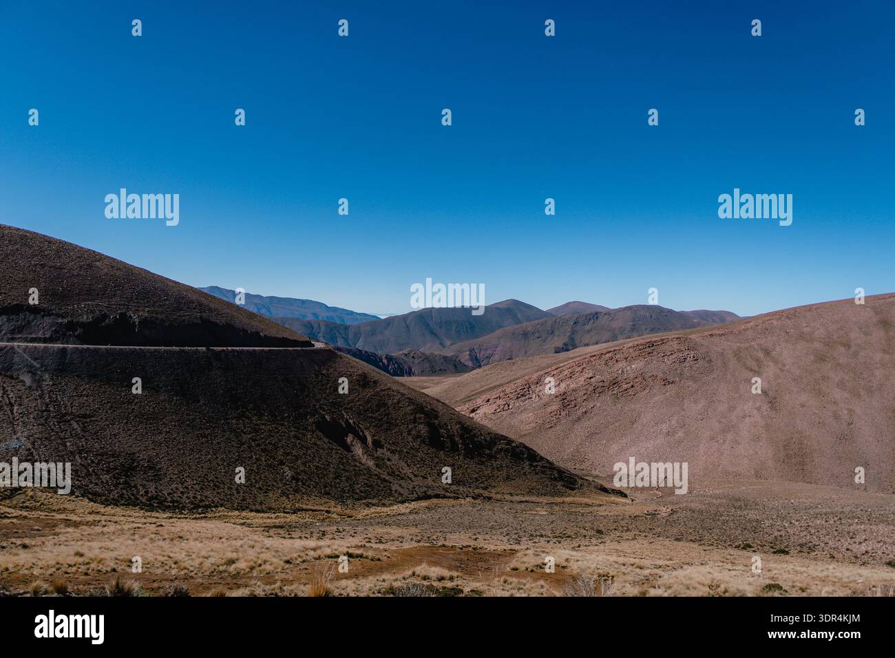 A vast, rocky desert landscape with a clear blue sky above. The ...