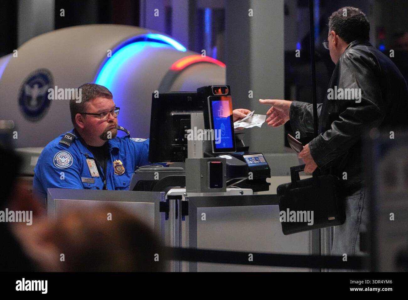 A TSA officer, left, hands a boarding pass back to a traveler at ...
