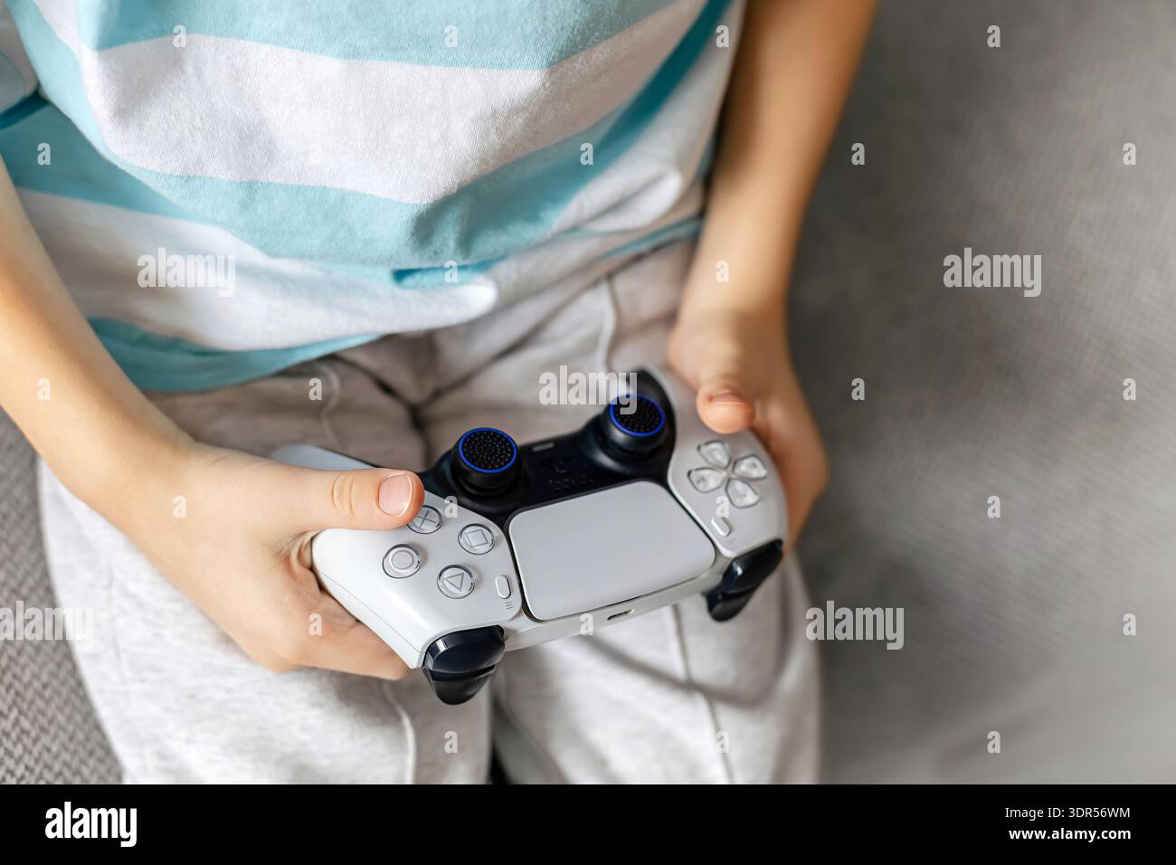 Child holding wireless game controller at home. Close up of kid playing ...