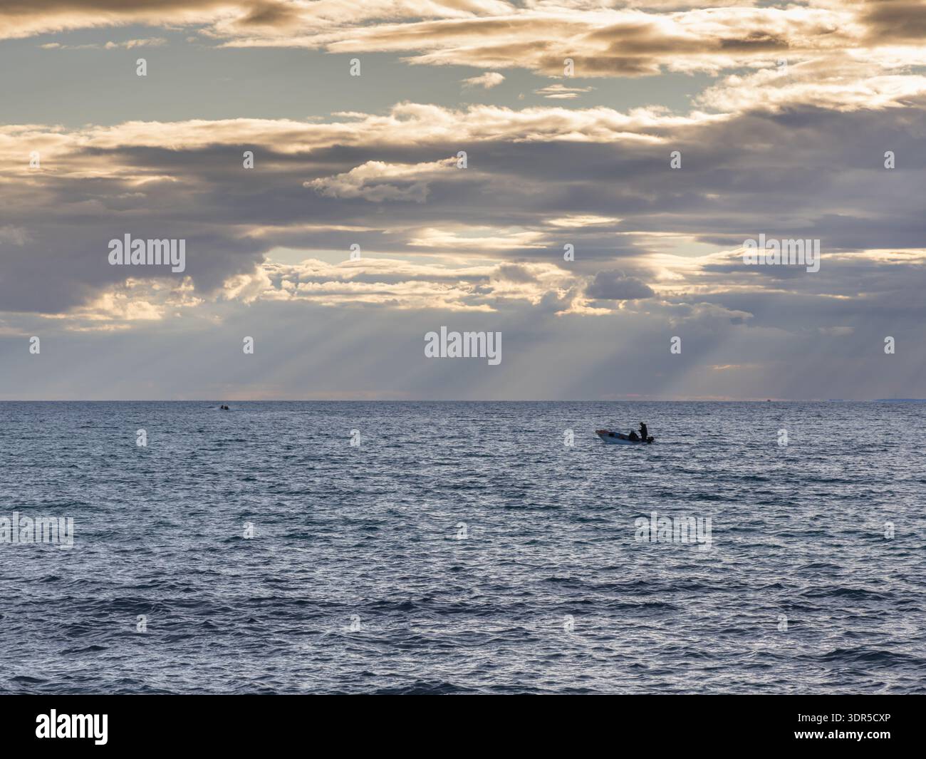 A lone fishing boat floats on the calm Mediterranean waters under a ...