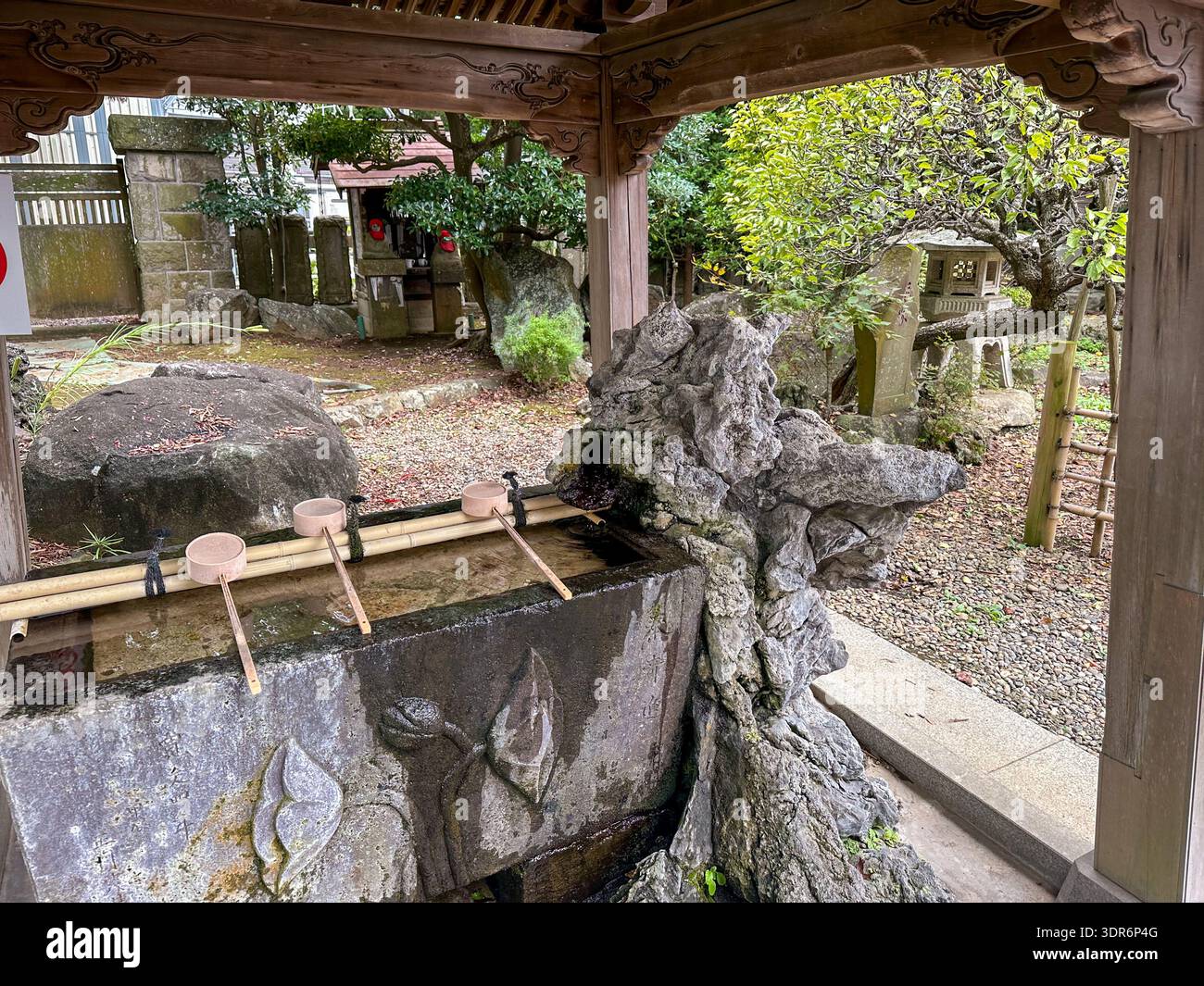 Traditional purification fountain (chozuya) with stone basin and ladles ...