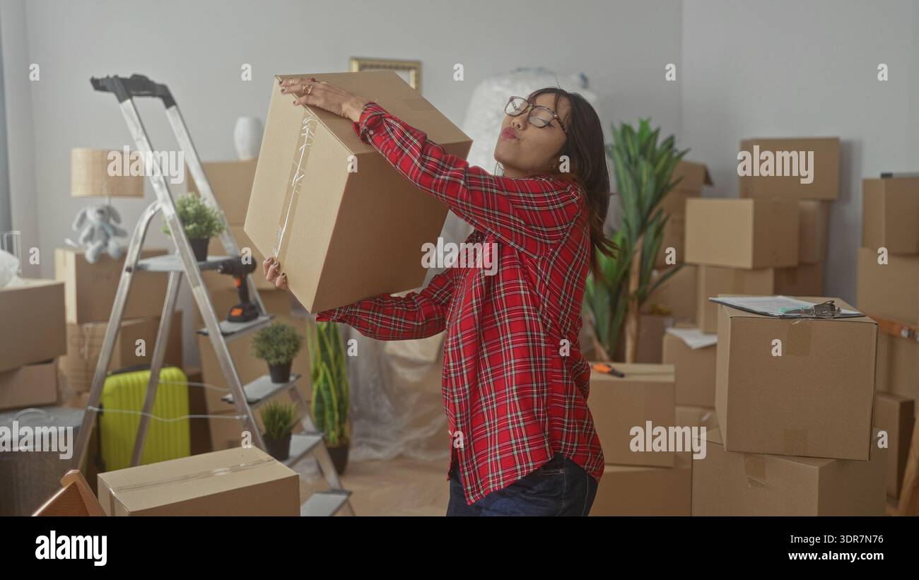 Woman lifting a cardboard box with hands visible in building filled ...