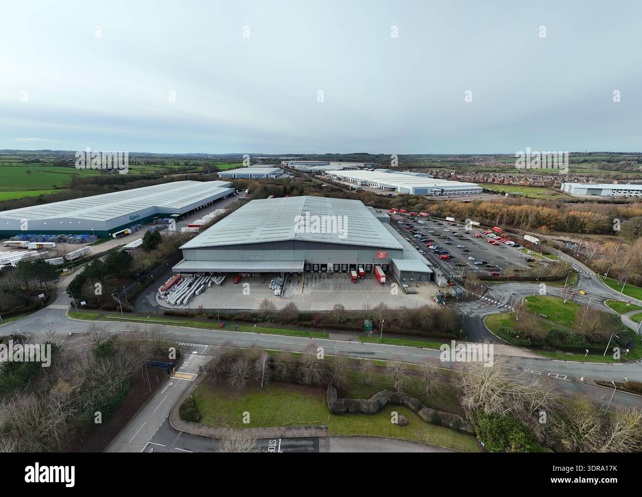 Aerial view of a large warehouse complex with rows of parked vehicles ...