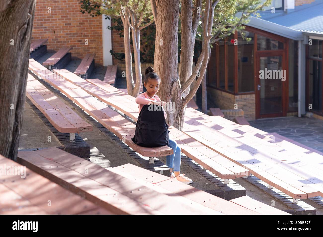 Sitting on bench, african american girl in school uniform looking ...