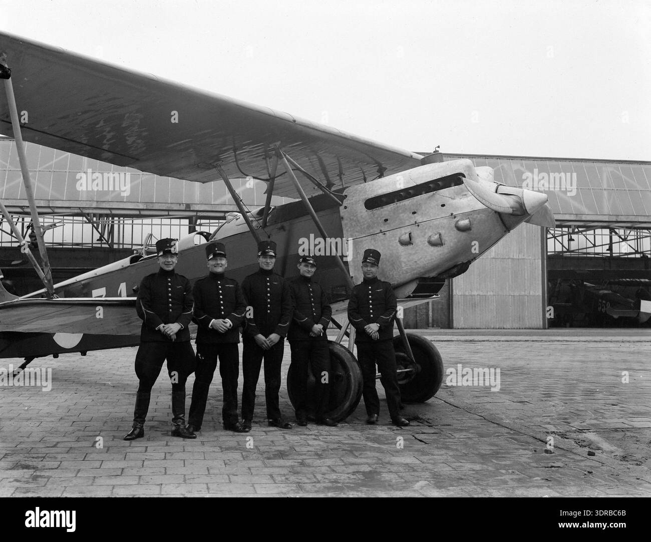 Five Dutch Air Force pilots in black uniforms with tall caps stand by a ...