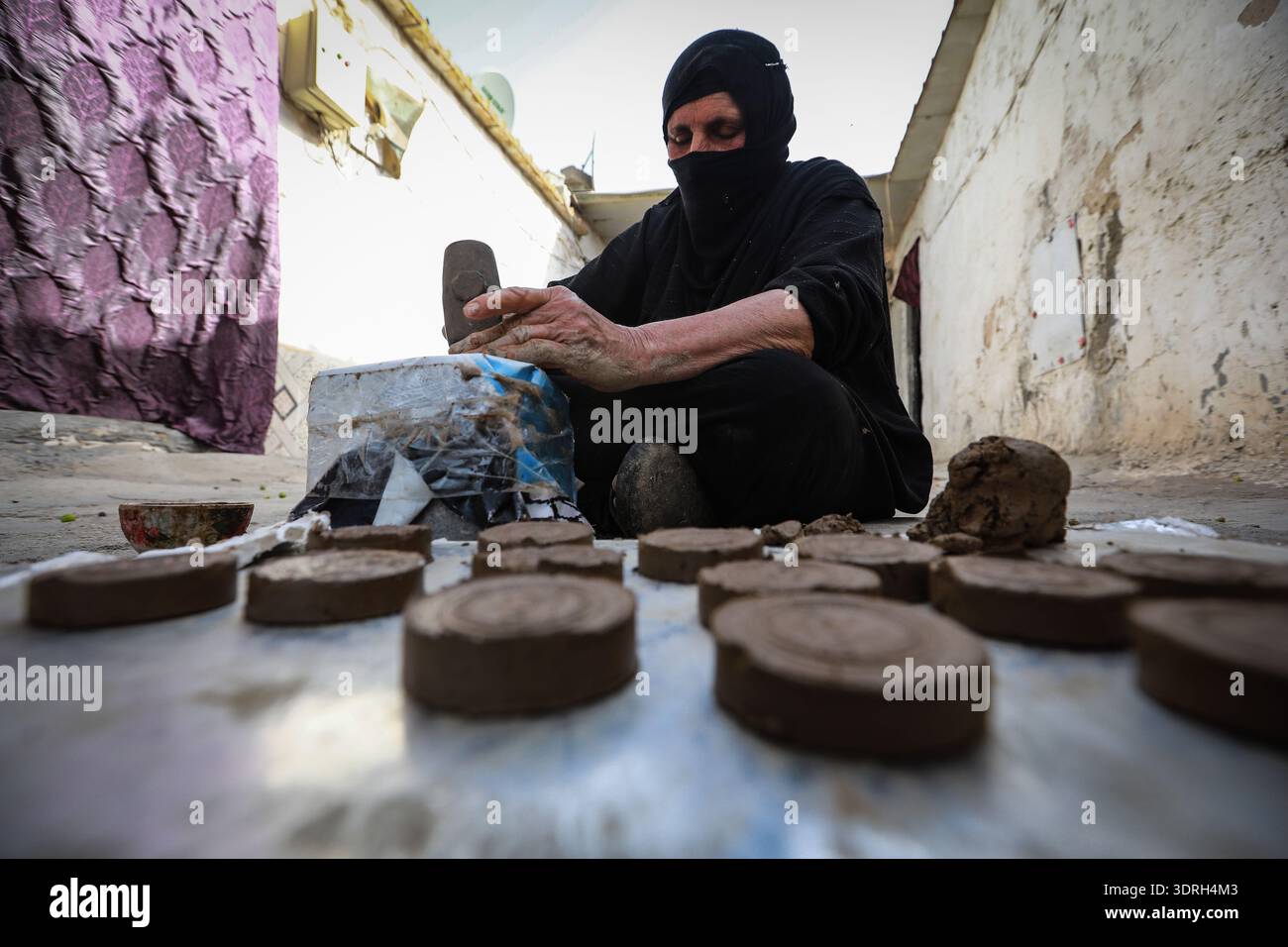 18 February 2026, Iraq, Karbala: Umm Ahmed, 75, shapes clay tablets by ...