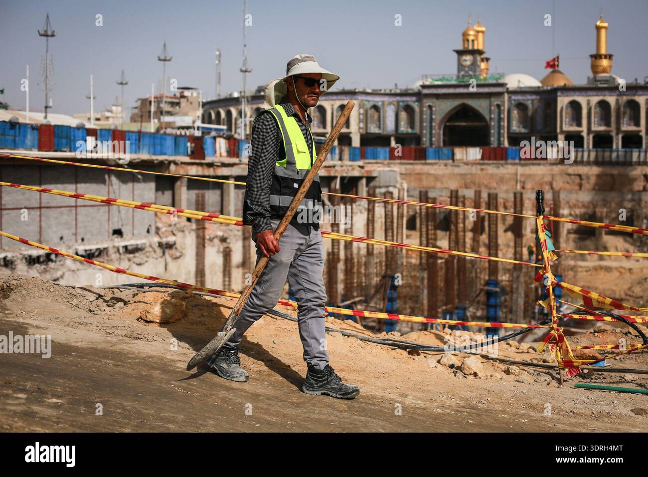 18 February 2026, Iraq, Karbala: A worker walks past excavation works ...
