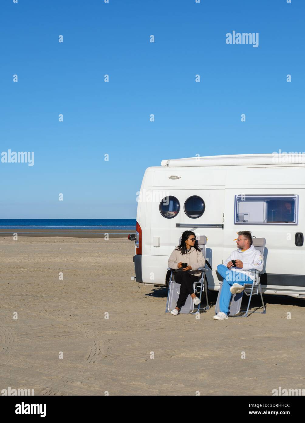 Two travelers enjoy a peaceful moment by the shore in Lakolk Strand ...