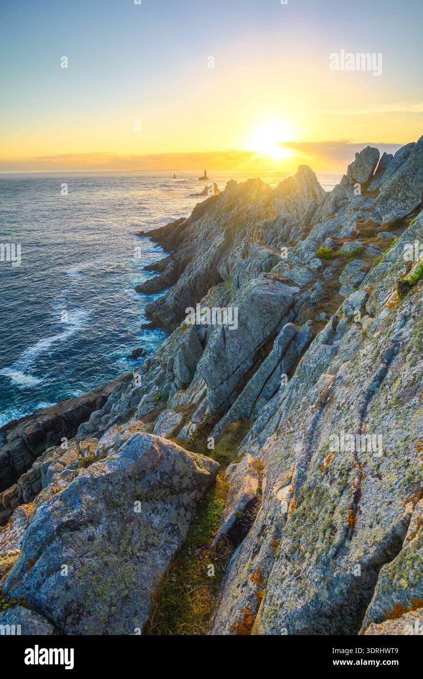Sunset over the rocky cliffs of Pointe du Raz with Atlantic Ocean waves ...