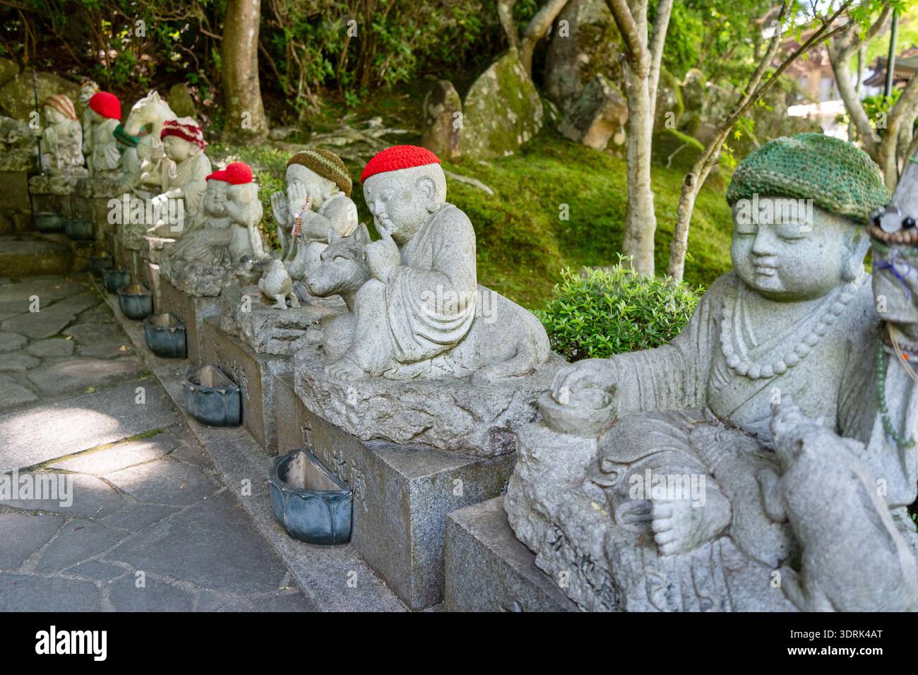 Group of moss-covered Jizo Bosatsu statues wearing red knit hats and ...