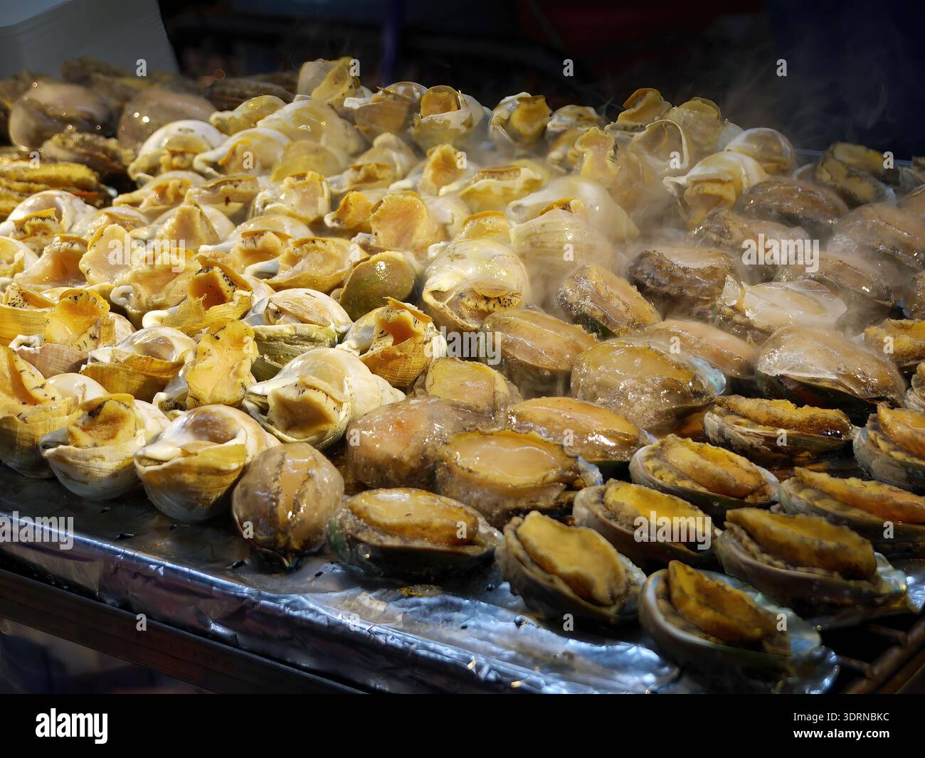 Freshly grilled abalone and sea snails sizzling on hot plate at Taiwan ...