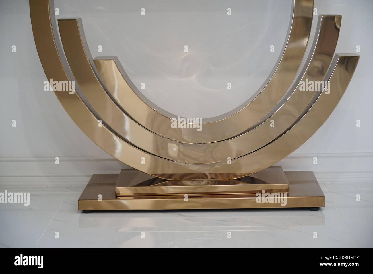 Gold and silver sculpture with three curved legs. The legs are ...