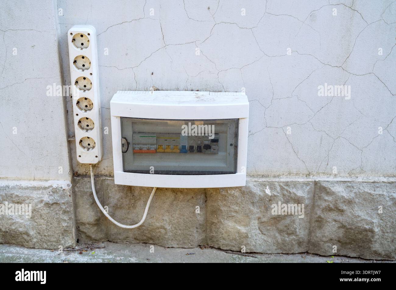 Electrical panel and power sockets mounted on a cracked exterior wall ...