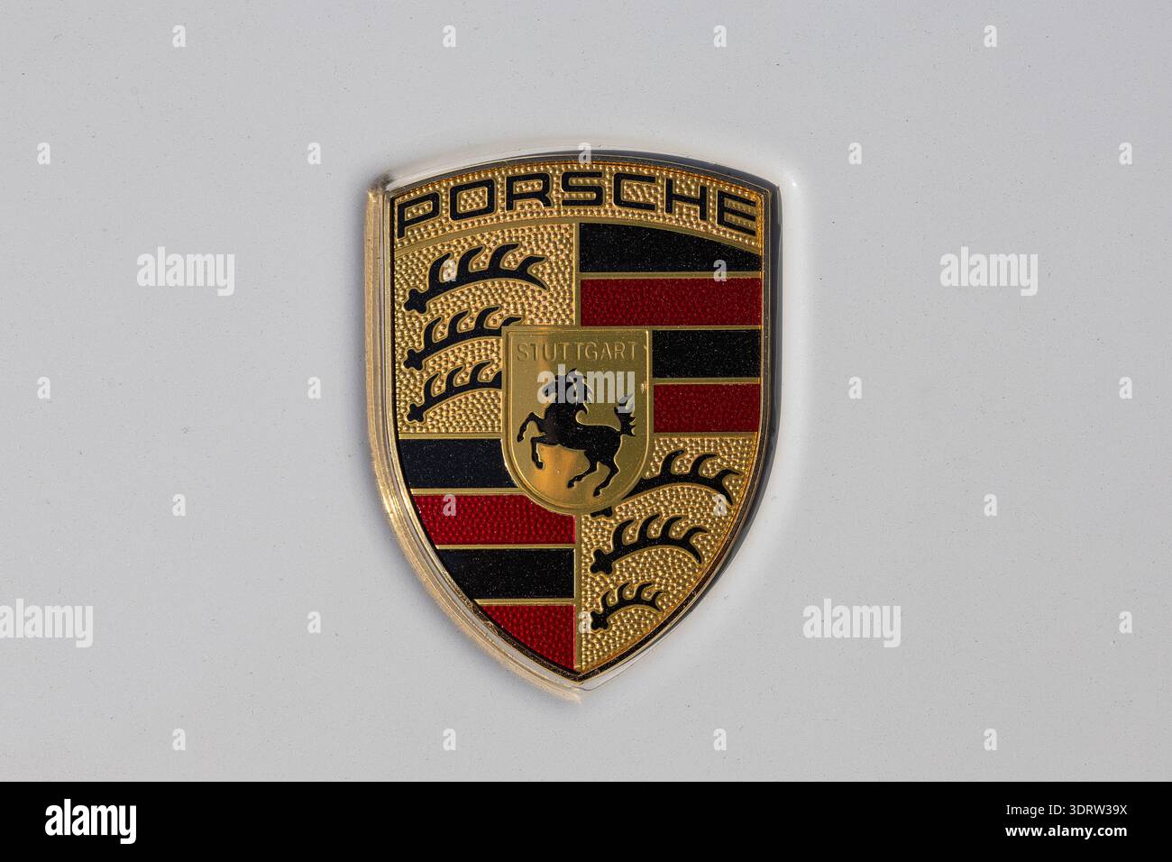 Close up of Porsche crest logo on white car hood, showcasing iconic ...