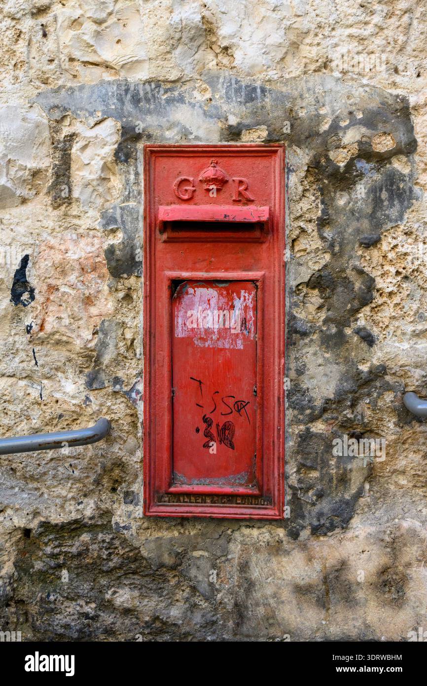 Red George Rex post box mounted on weathered stone wall, vintage ...