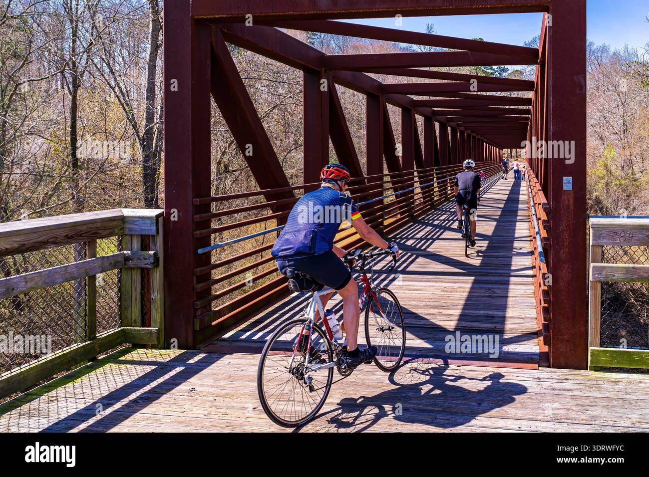 Raleigh, North Carolina, USA. Cyclists cross a pedestrian bridge along ...