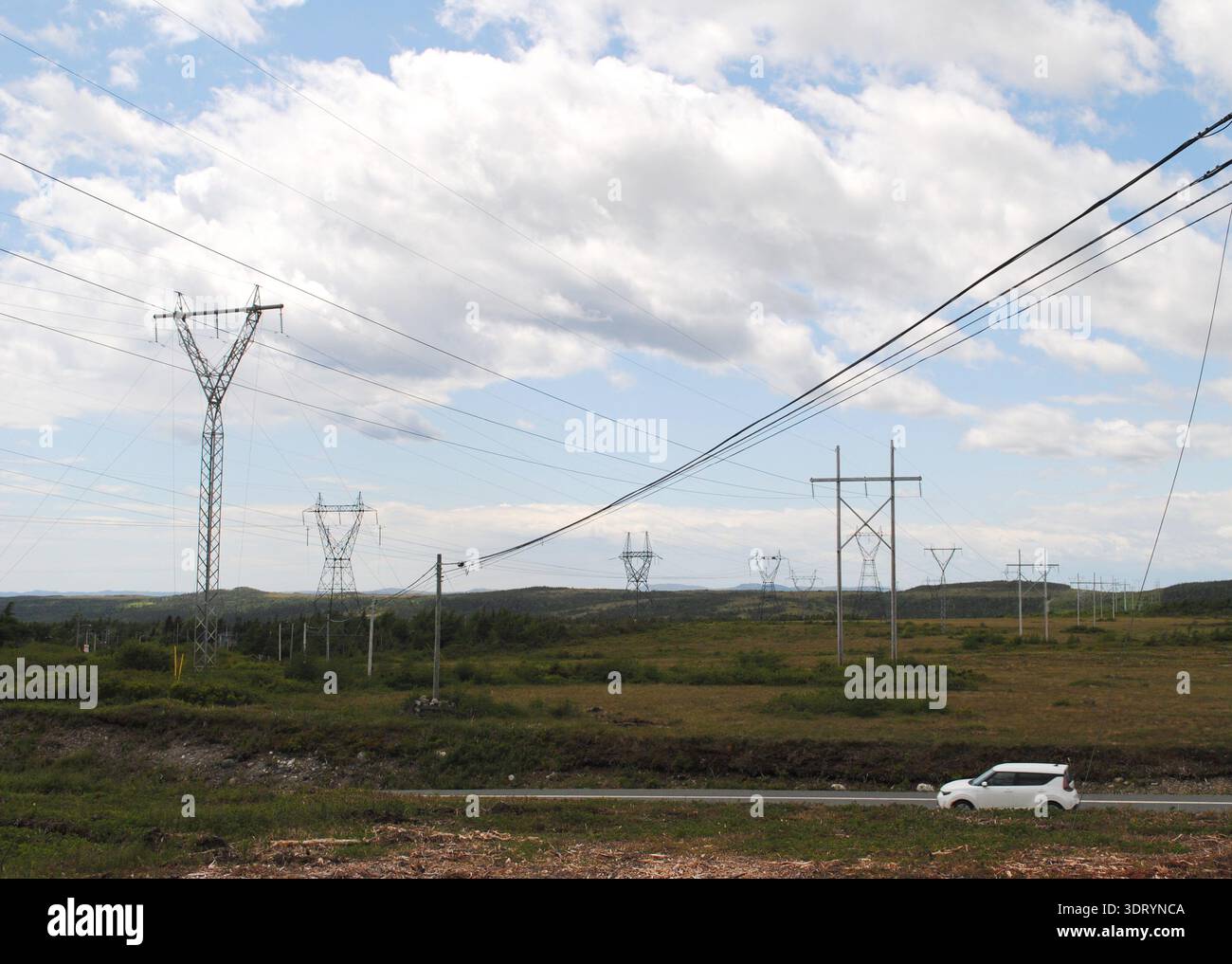 A car is shown driving by a valley of power lines near Come By Chance ...