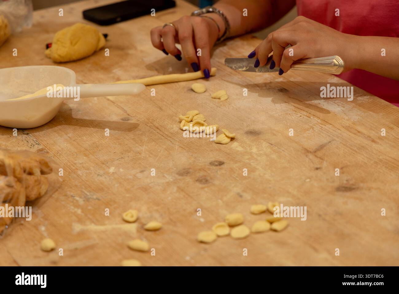 Woman sitting in the street and making typical pasta known as ...