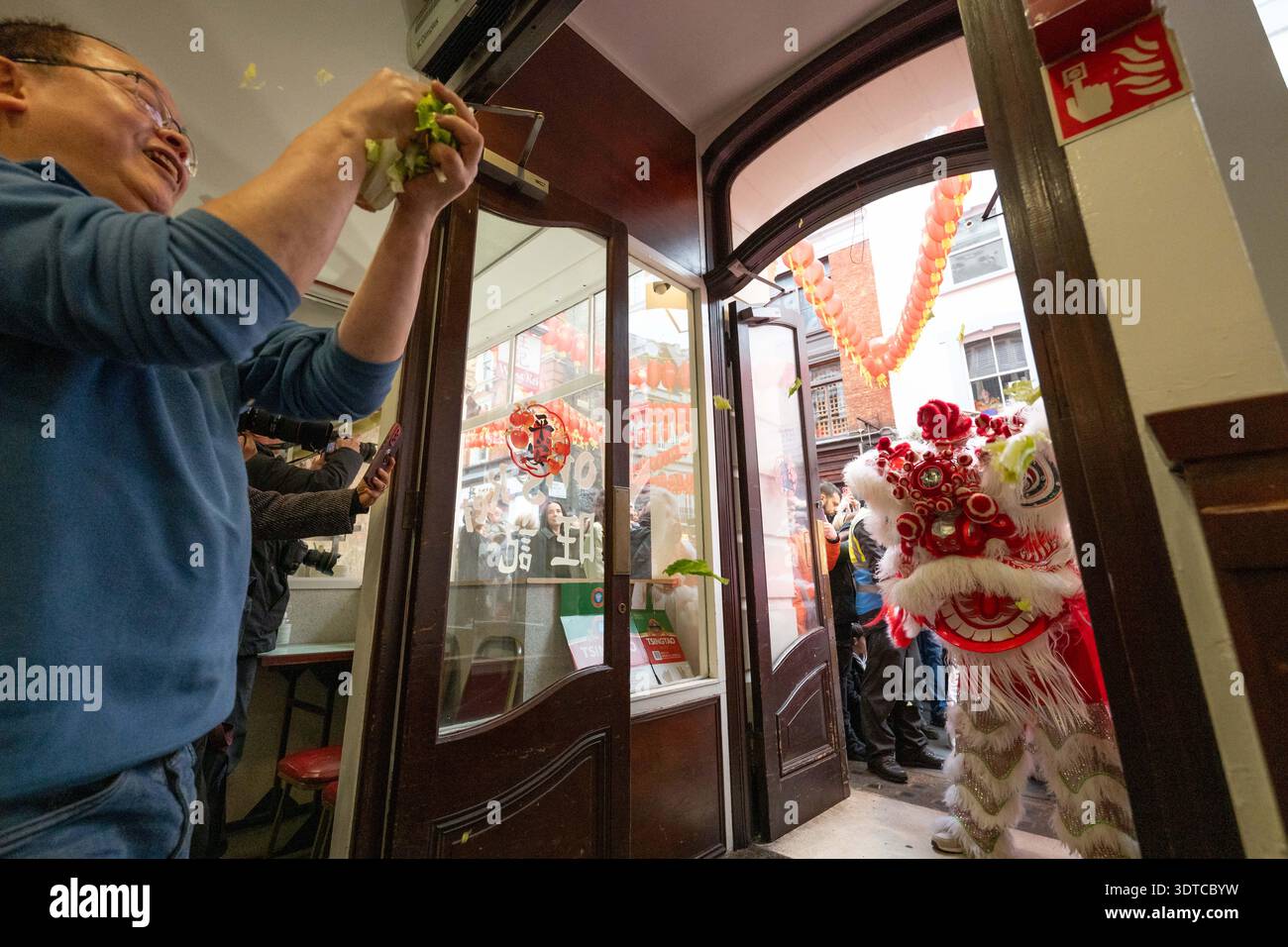 Performers in lion costume throw lettuce to the owner of the restaurant ...