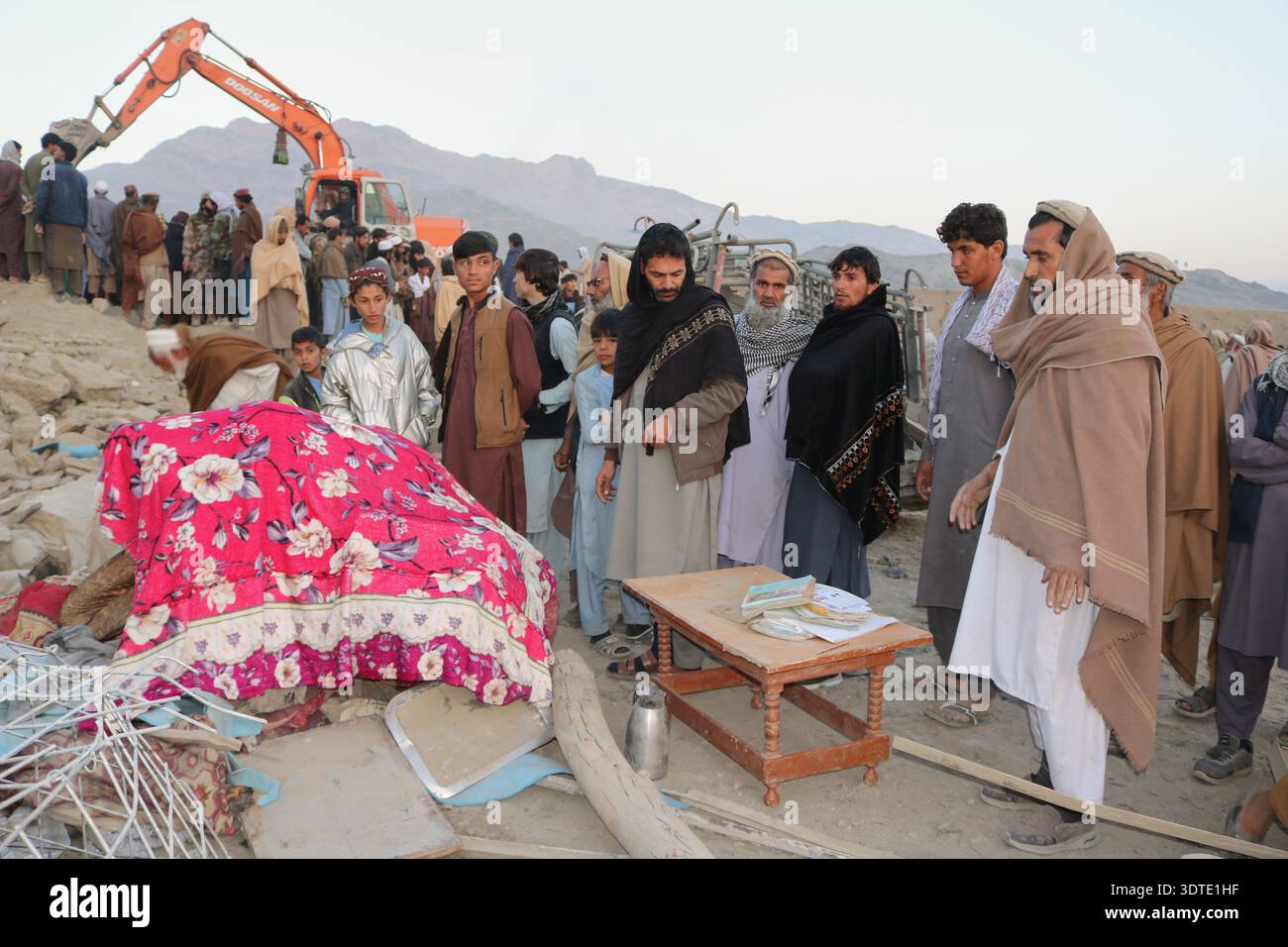 Local residents gather as bulldozer clears the rubble of a house hit by ...