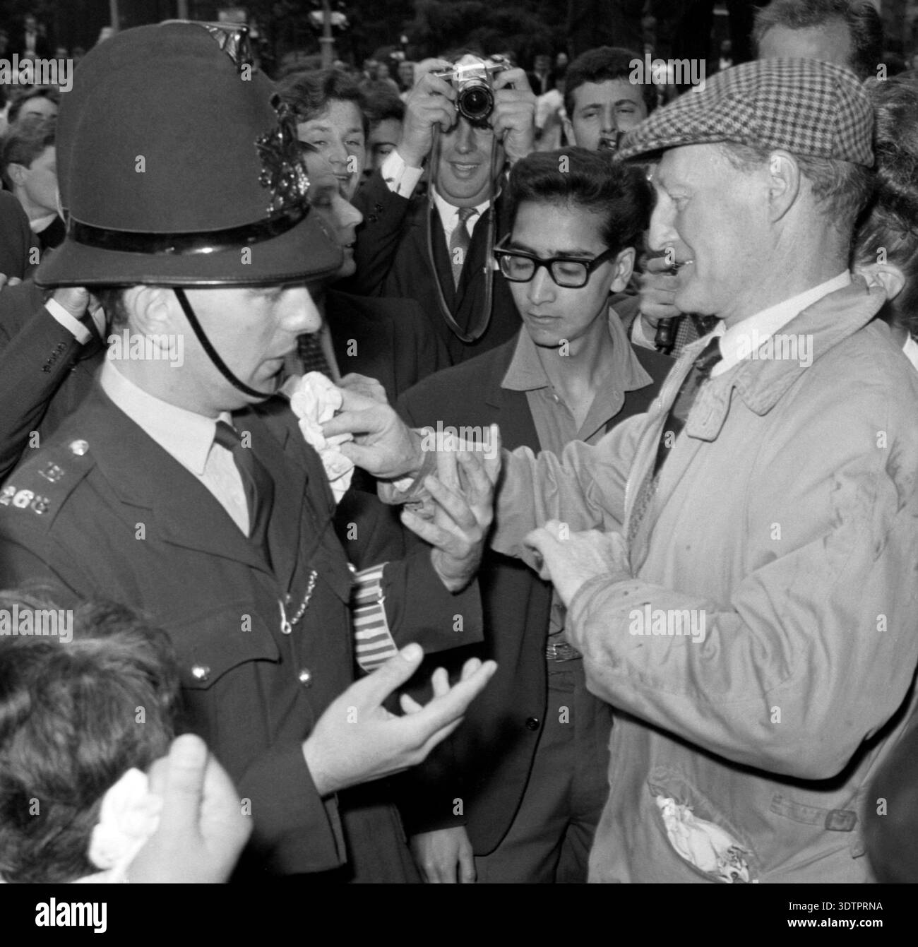 A member of the crowd wipes down a policeman's tunic after he had been ...