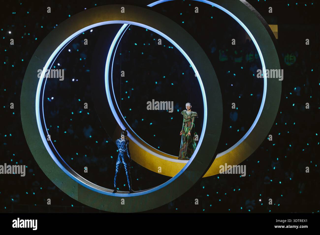 Two aerial actors perform next to the rings representing the city and ...