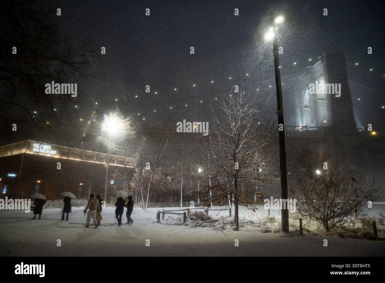 Pedestrians walks near the Brooklyn Bridge as snow falls during a major ...