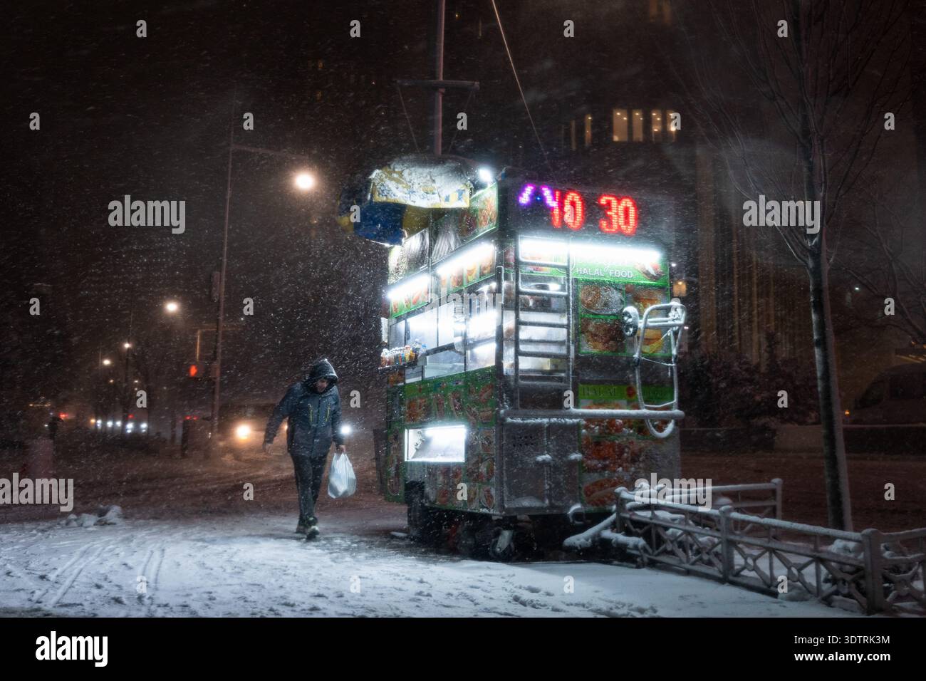 A pedestrian approaches a food cart as heavy snow falls during a major ...