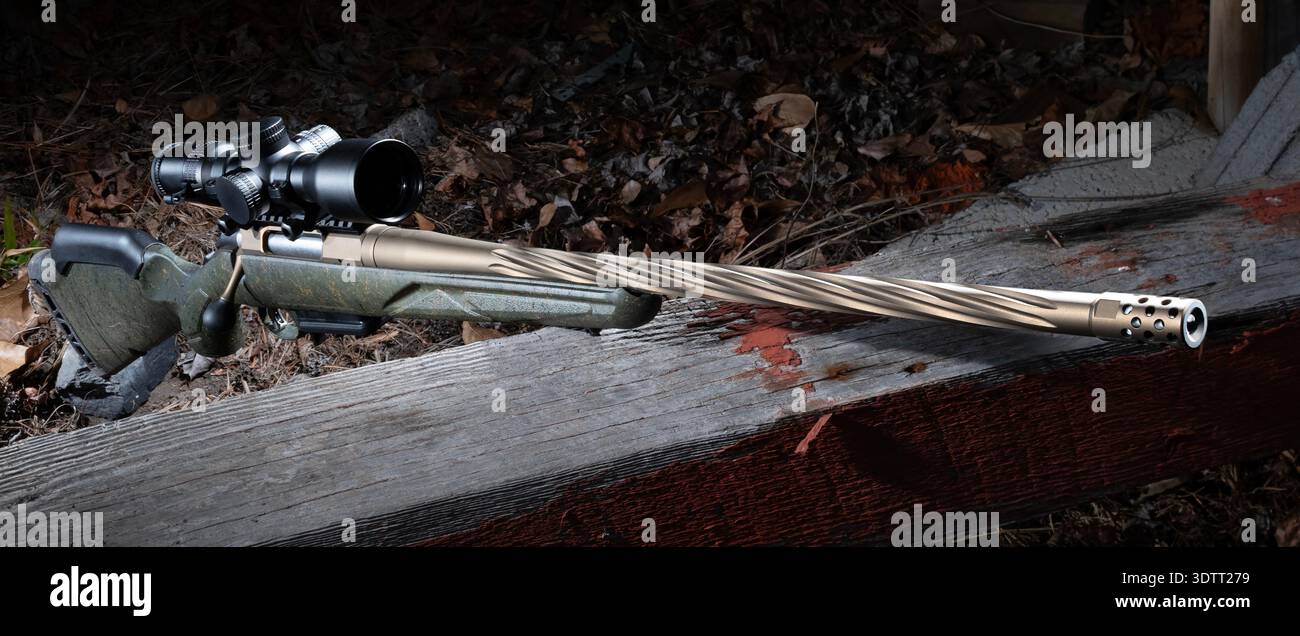 Gold colored spiral fluted battel on a bolt action rifle with scope ...