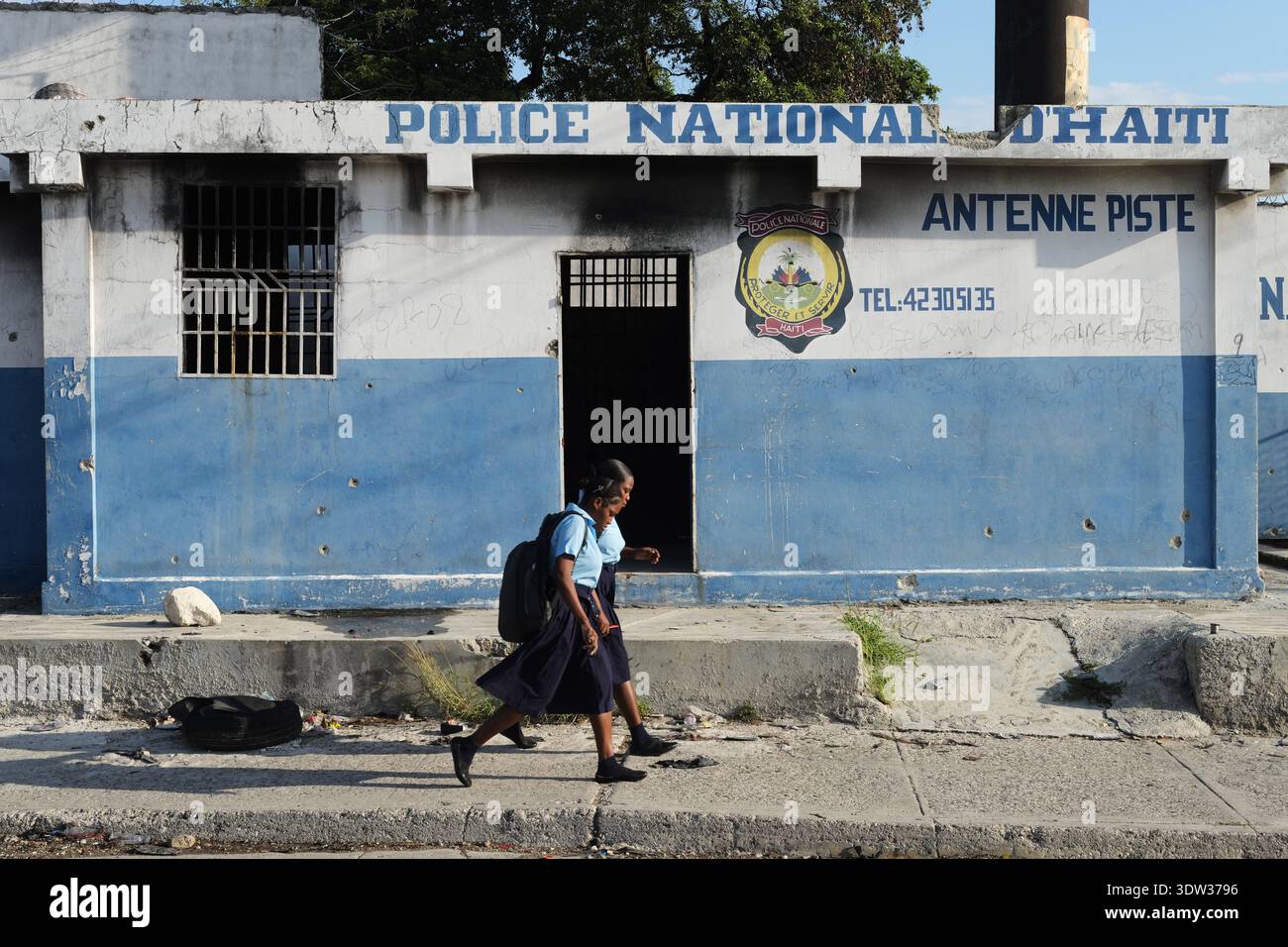 Students walk past a police station that was set on fire by armed gangs ...
