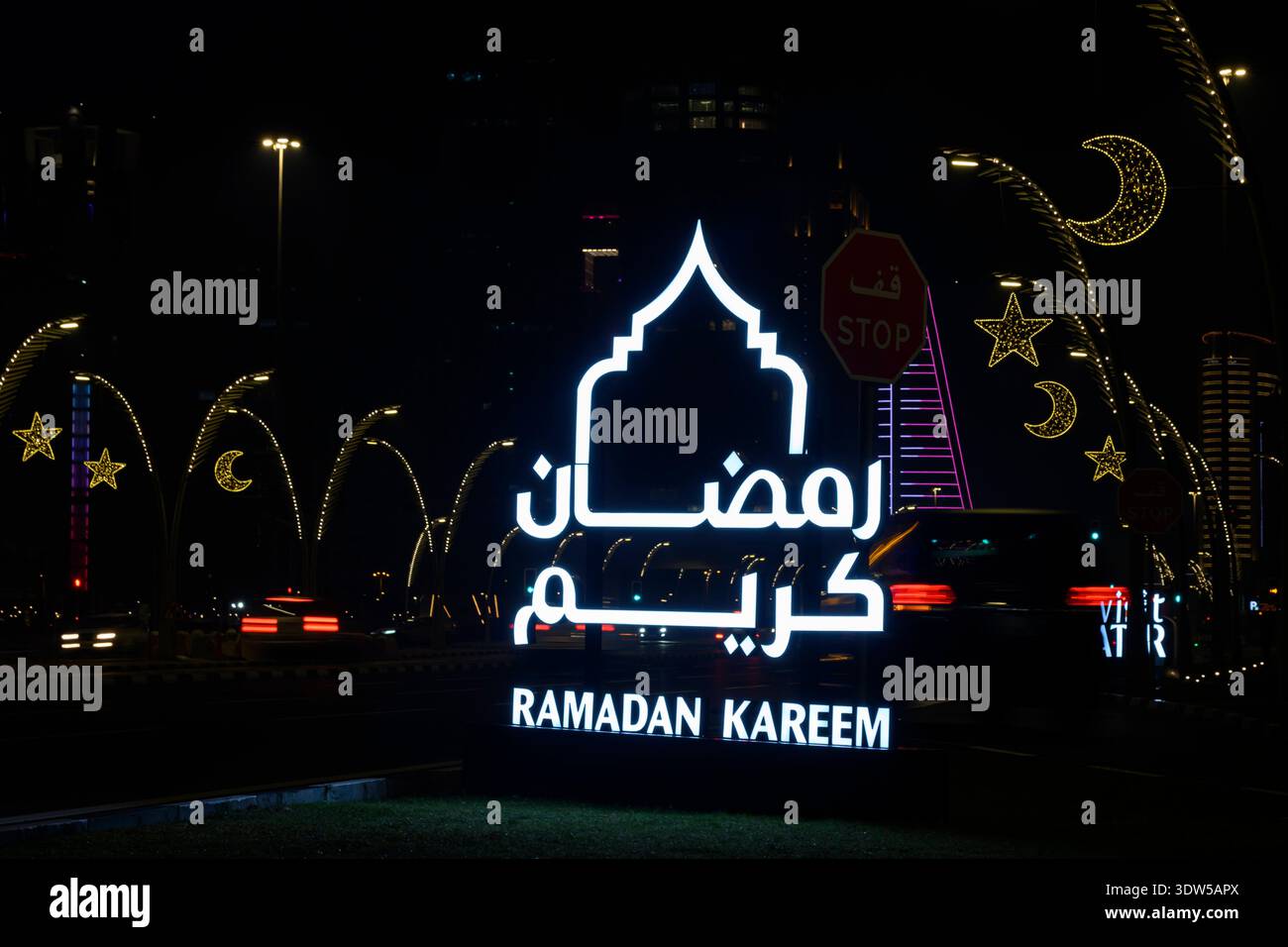 Ramadan lighting in Doha street. Vehicles drive along a road decorated ...