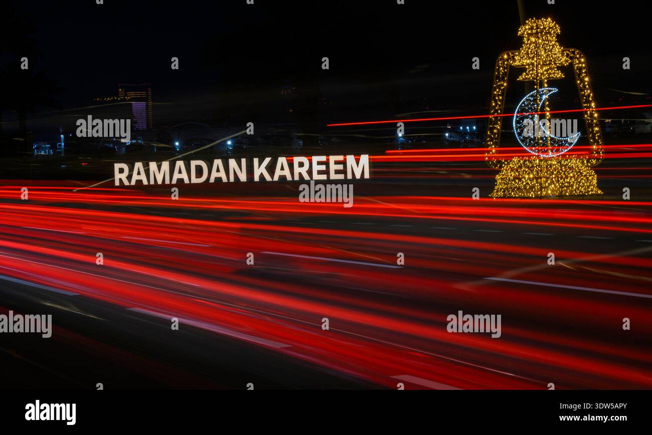 Ramadan lighting in Doha street. Vehicles drive along a road decorated ...