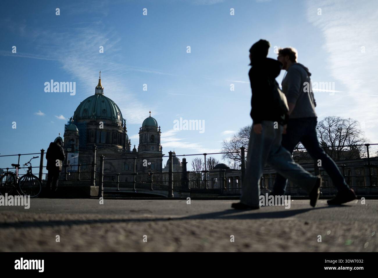 25 February 2026, Berlin: Passers-by walk along the Spree in the ...