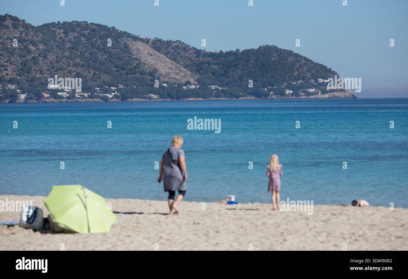 25 February 2026, Spain, Son Servera: People sunbathe on a beach in ...