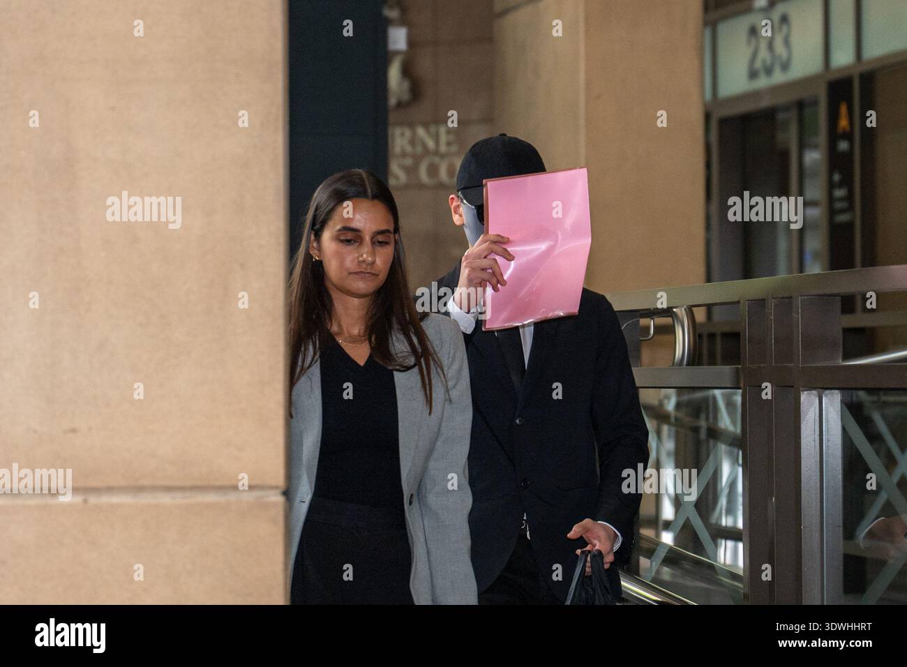 Ryan Cho, hiding his face, exits the Melbourne Magistrates Court, in ...