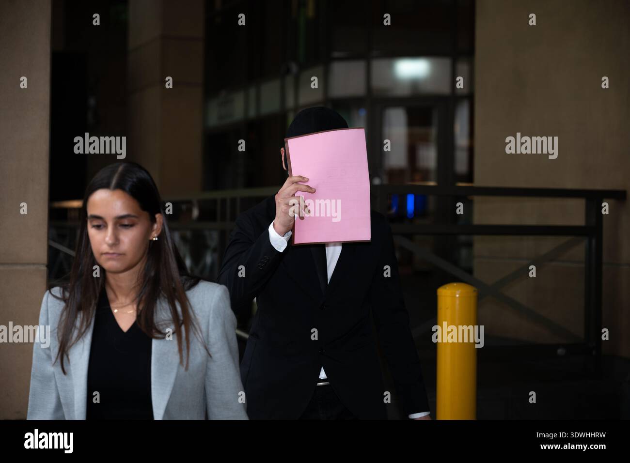 Ryan Cho, hiding his face, exits the Melbourne Magistrates Court, in ...