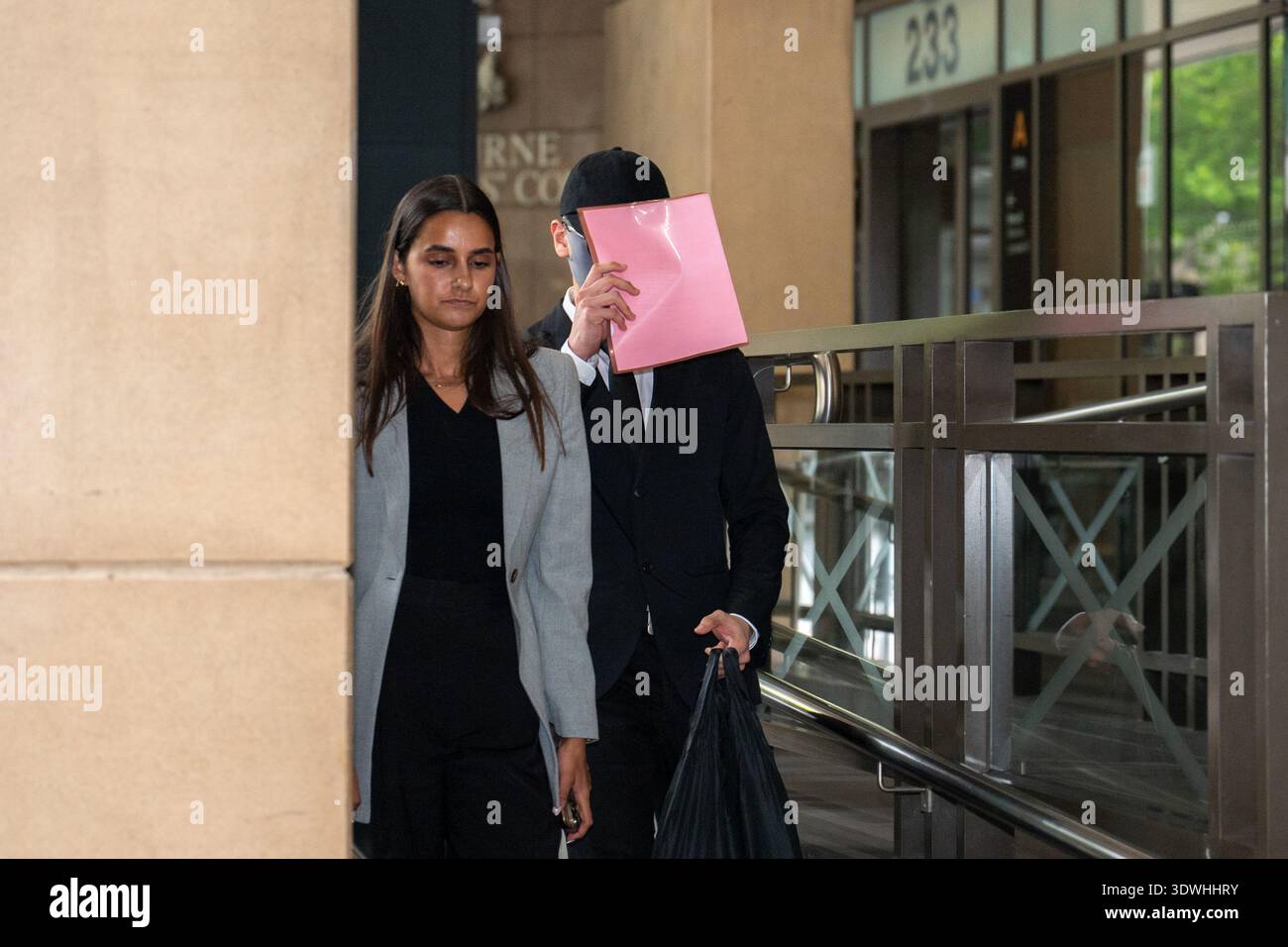 Ryan Cho, hiding his face, exits the Melbourne Magistrates Court, in ...