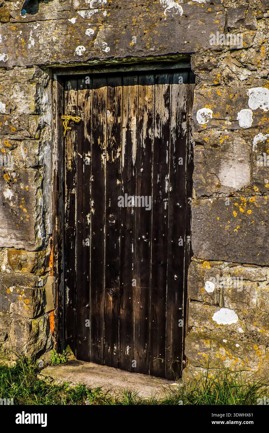 Weathered wooden door is set into the thick stone wall of a traditional ...