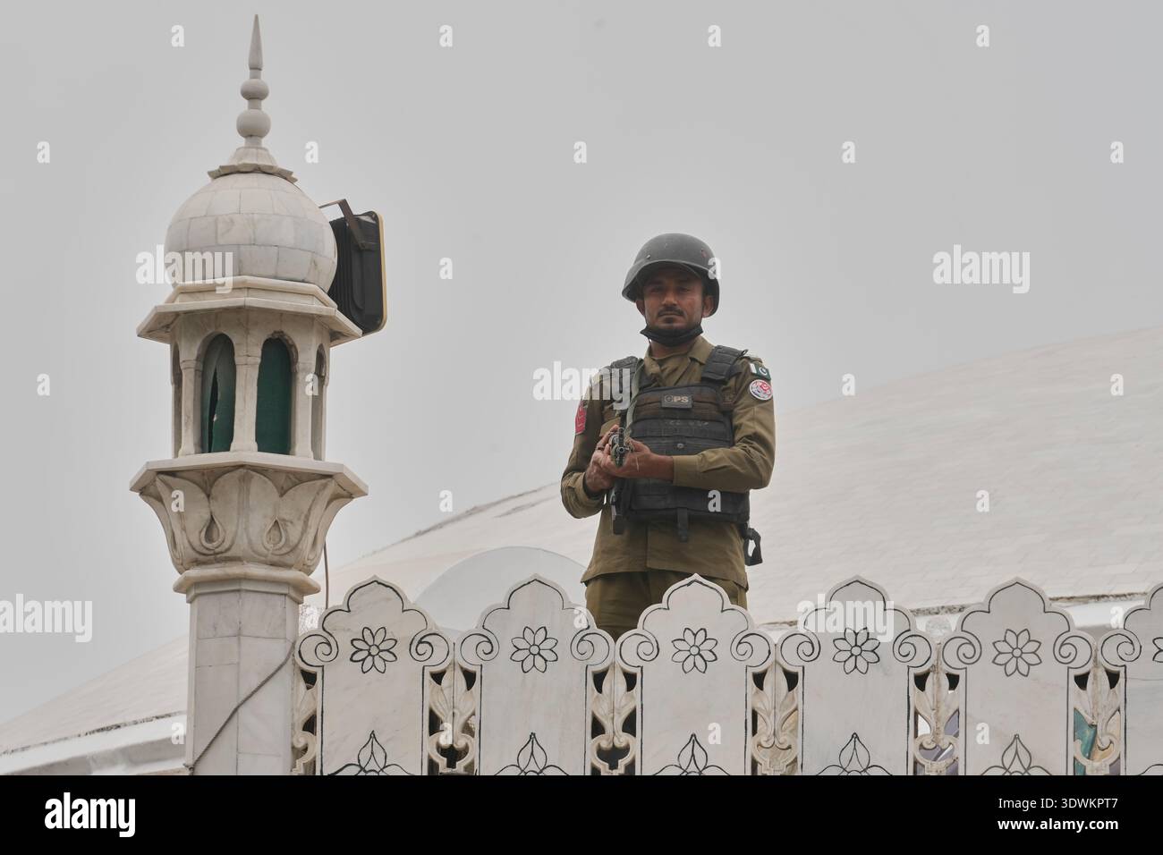 Police officer stands guard on the roof of a mosque as Muslims offer ...