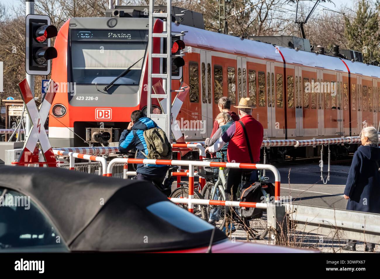 Bahnübergang der Münchener S-Bahn, Radfahrer warten vor der rotern ...