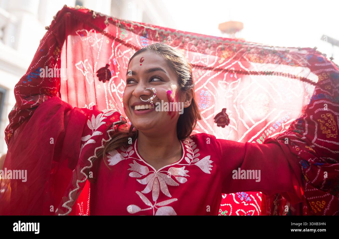 A woman smeared with vermilion powder smiles during the holi festival ...