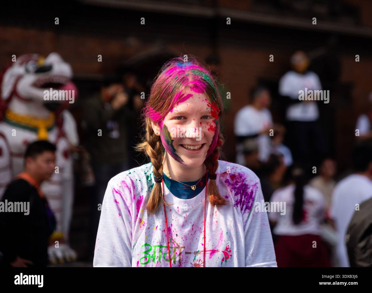 A woman smeared with vermilion powder smiles during the holi festival ...