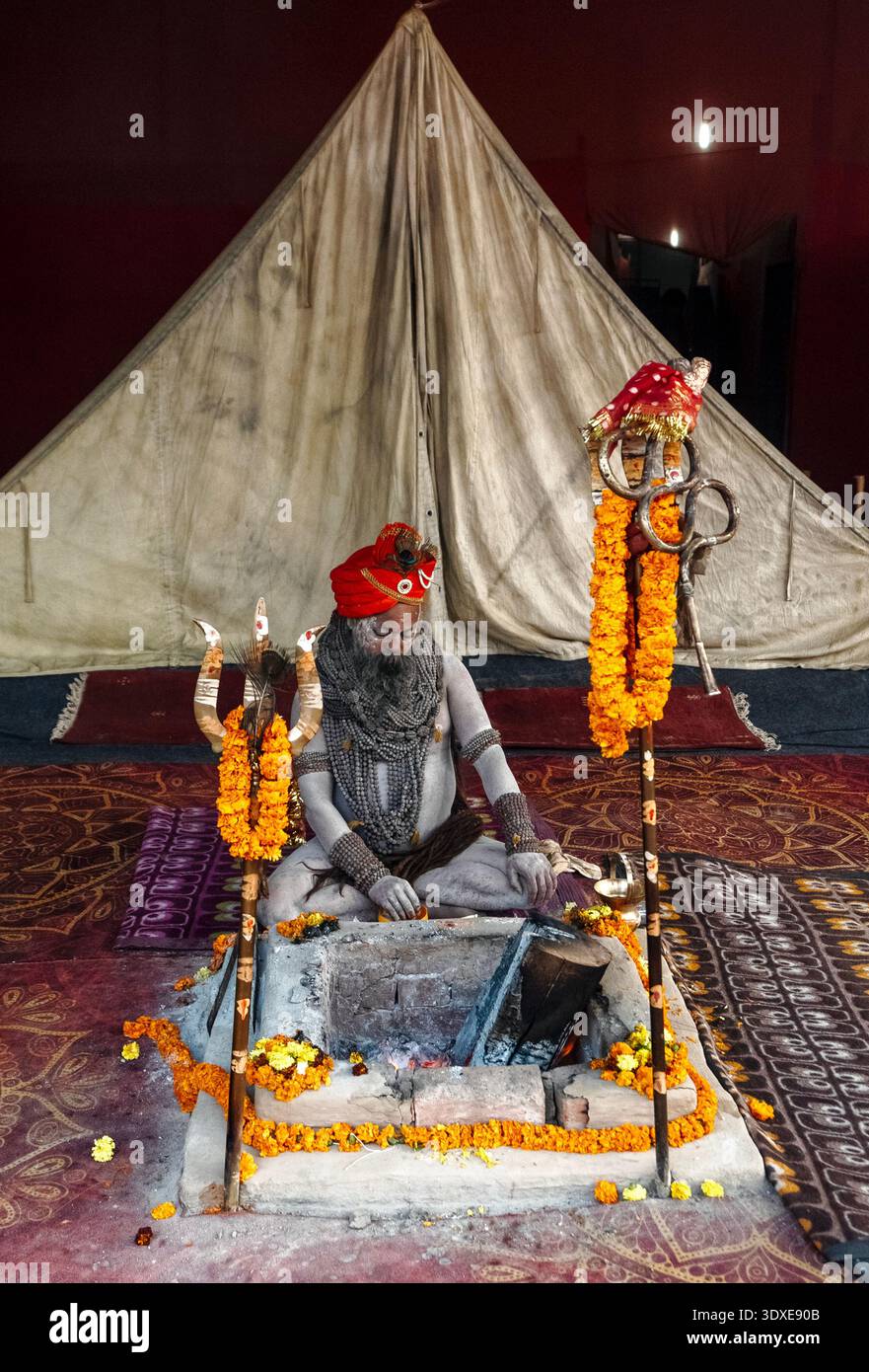 Hindu sadhu performing sacred fire ritual inside tent during Kumbh Mela ...