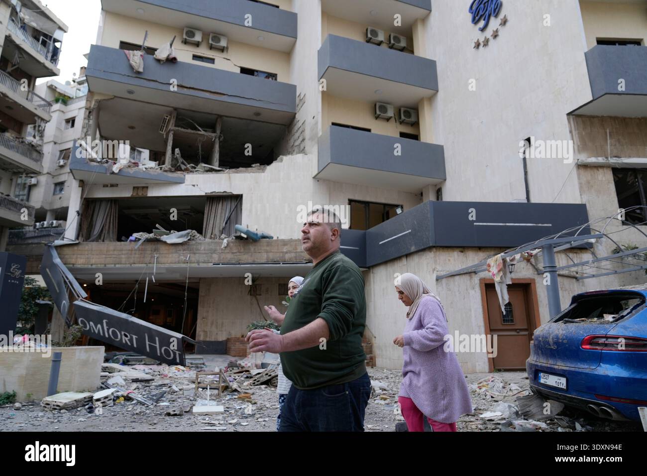 People pass in front of a damaged hotel that was hit by an Israeli ...