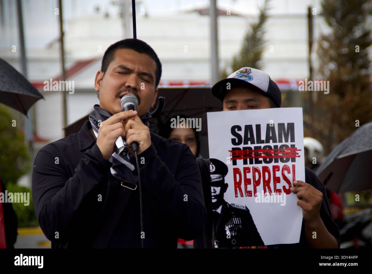 Syahdan Husein speaks into a microphone as protesters hold signs during ...