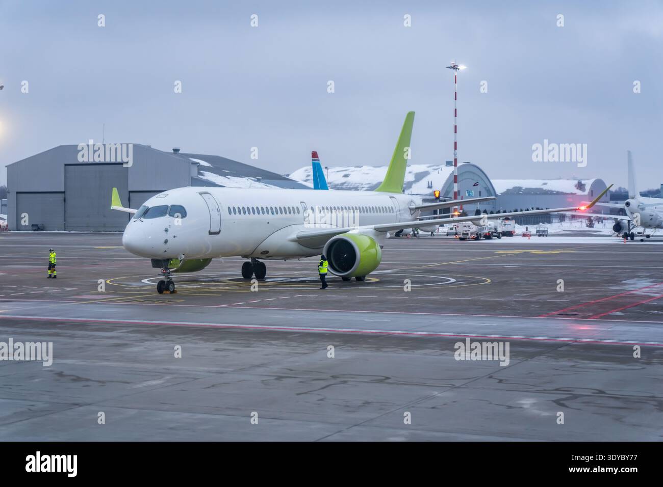 Passenger jet parked on winter airport apron with ground crew in high ...