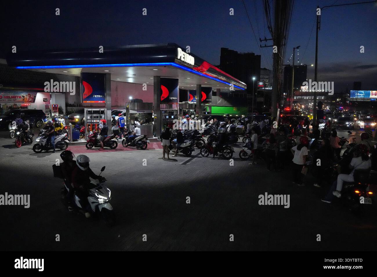 Motorists queue at a gasoline station a day before the implementation ...