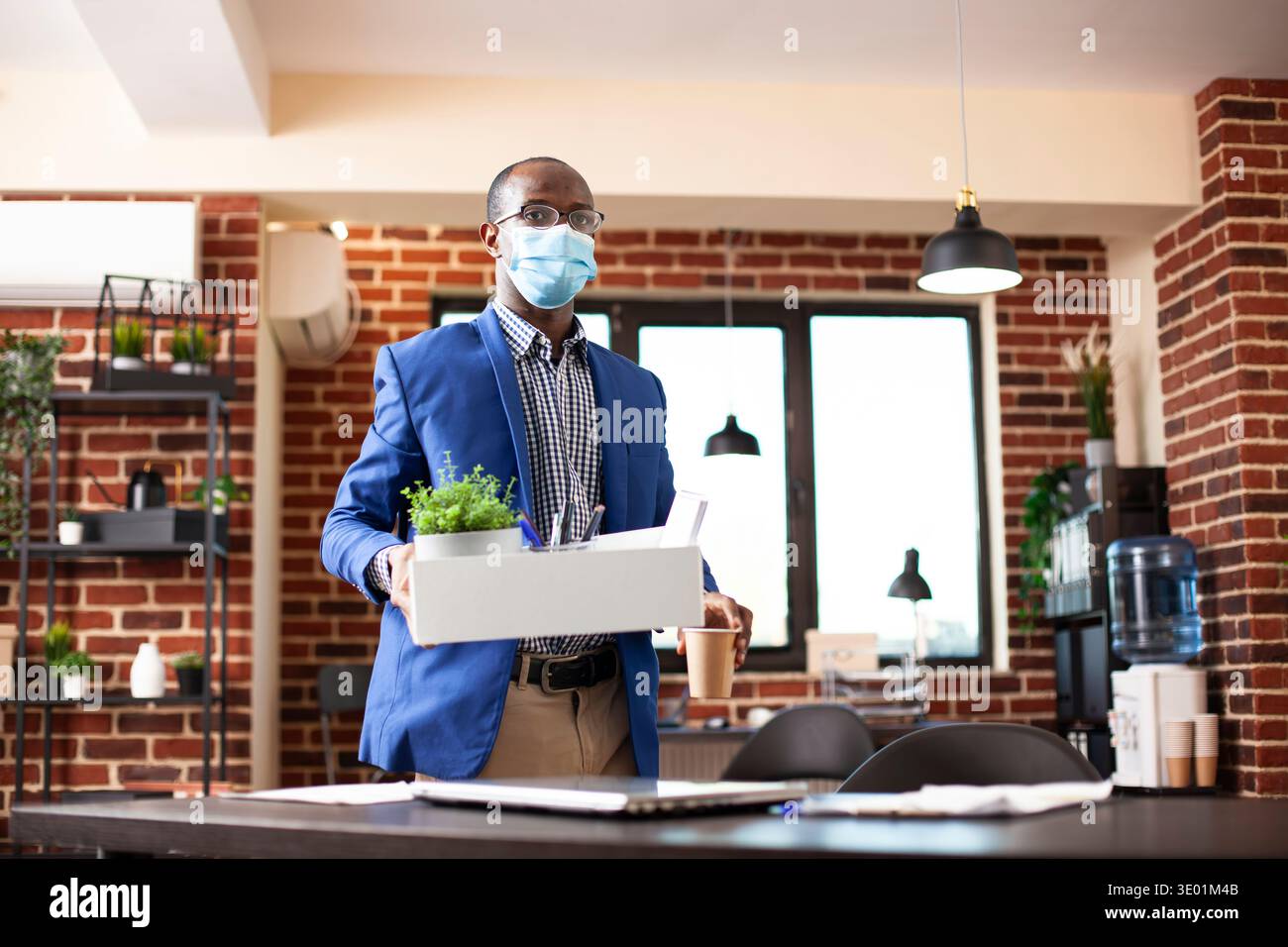 Businessman in suit is holding white box and coffee cup, walking to ...